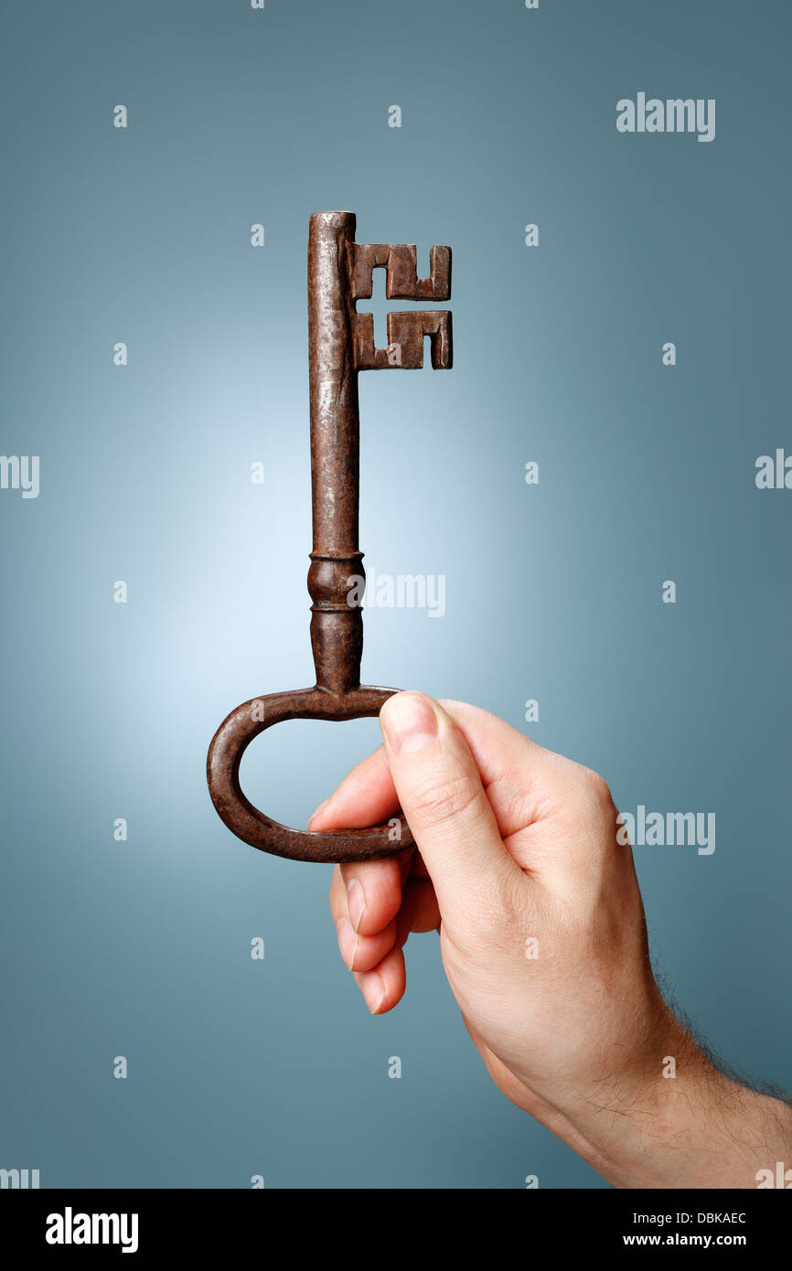 Man holding a big old key in his hand Stock Photo - Alamy