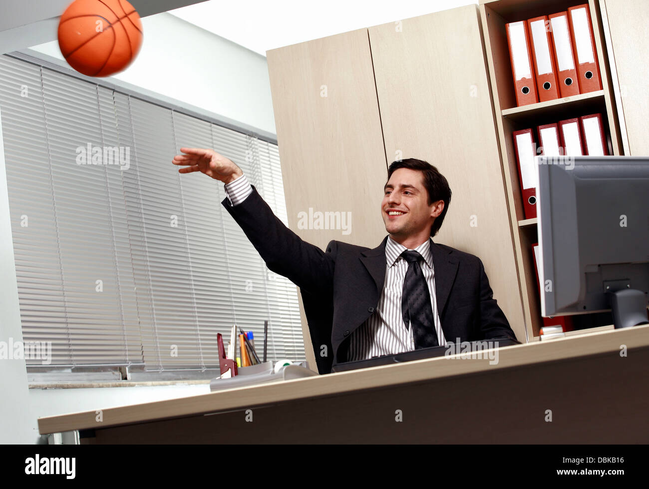 Office worker at desk playing with a basketball Stock Photo - Alamy