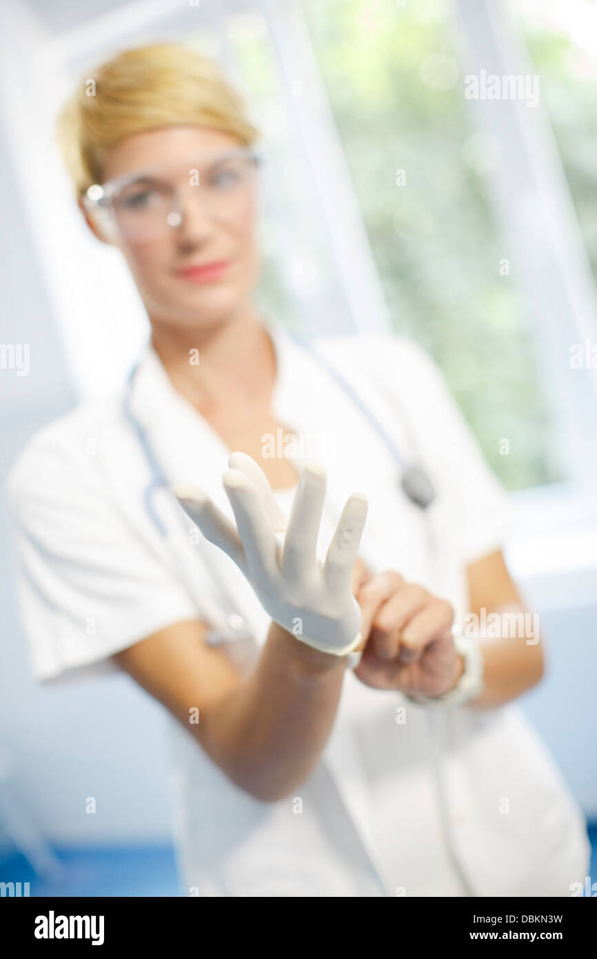 Female Doctor Putting On Surgical Gloves Stock Photo - Alamy
