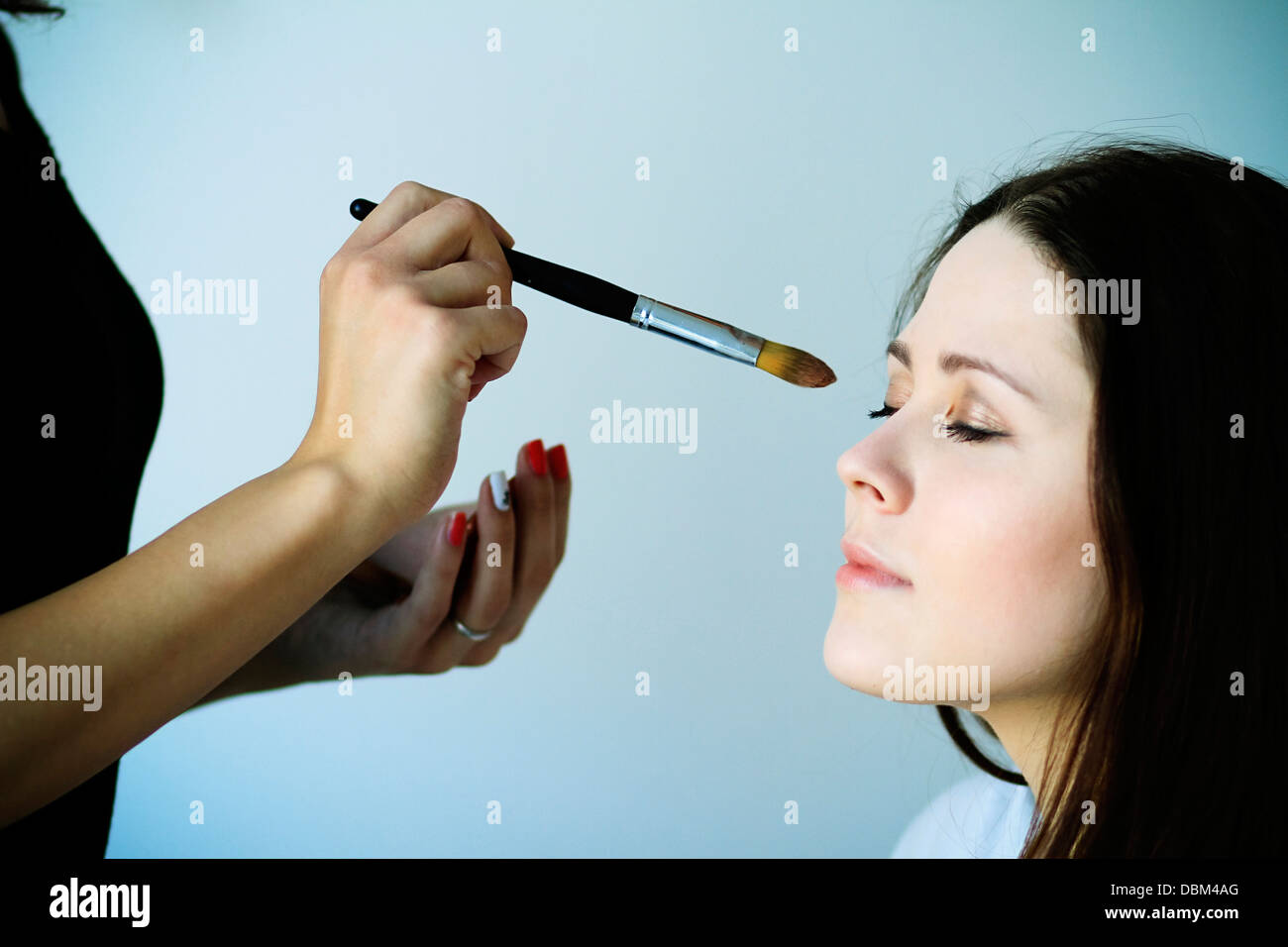 Stylist applying eyeshadow to young woman's face, Copenhagen, Denmark ...