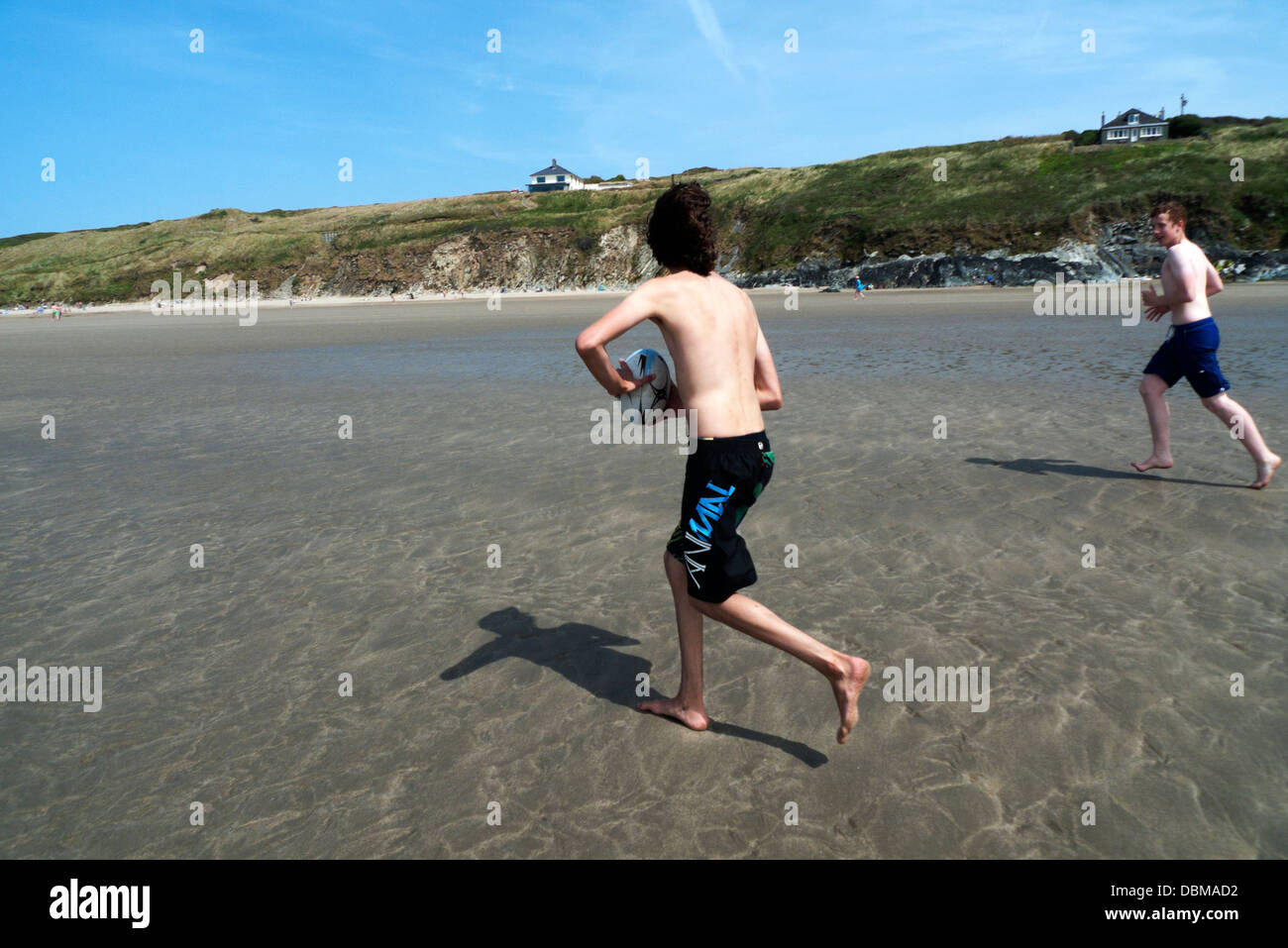 Boys running and playing with a rugby ball on Whitesands Bay beach ...