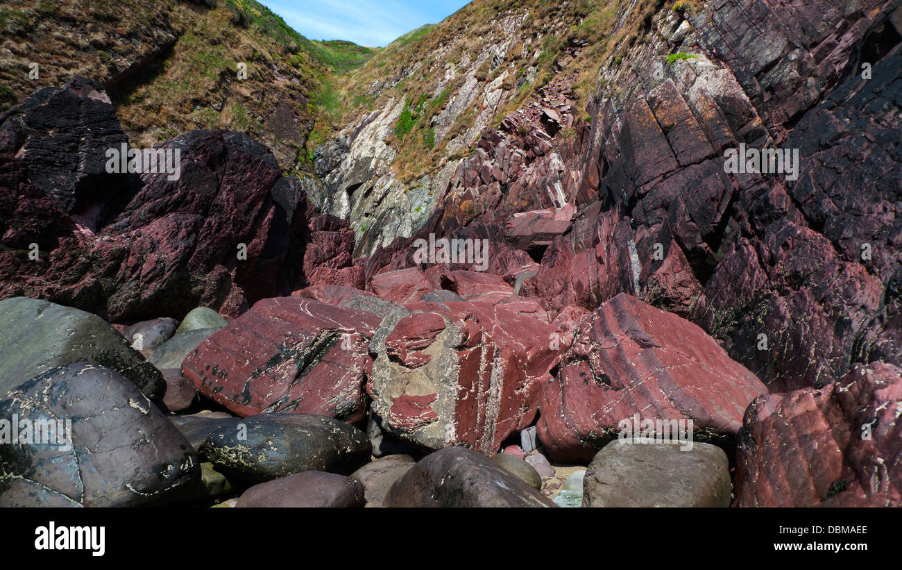 Red rocks on the beach at Caerfai Bay, St Davids, Pembrokeshire Wales ...