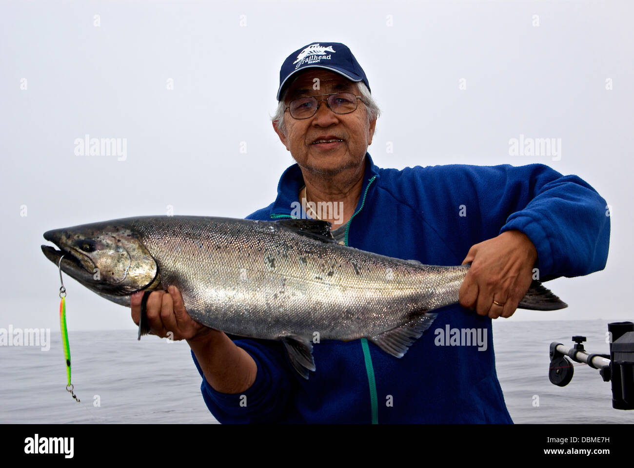 Happy smiling Asian angler holding sport caught chinook salmon trolling ...