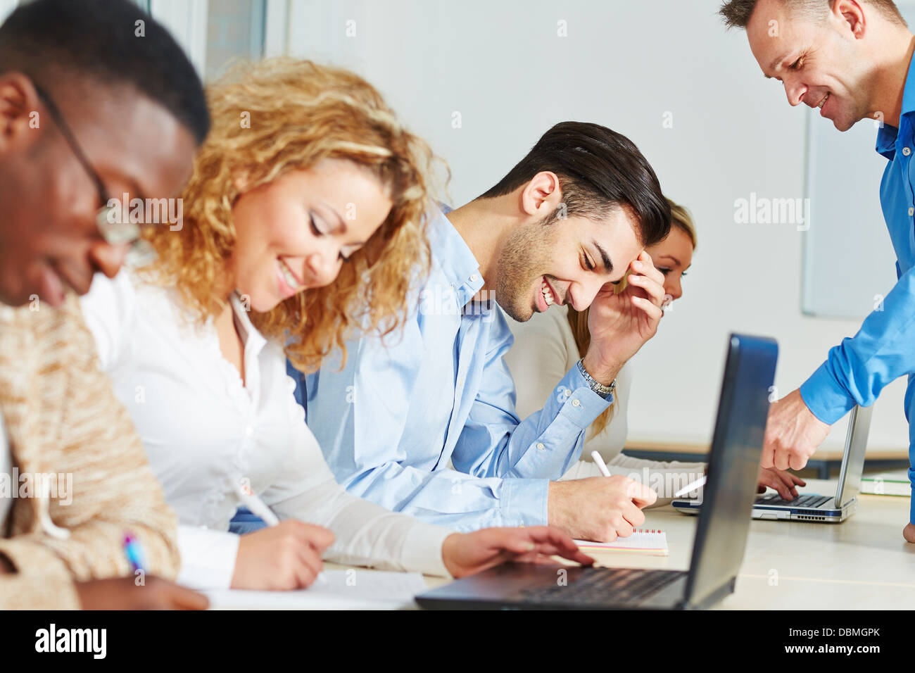 Teacher helping some students in a class in the university Stock Photo ...