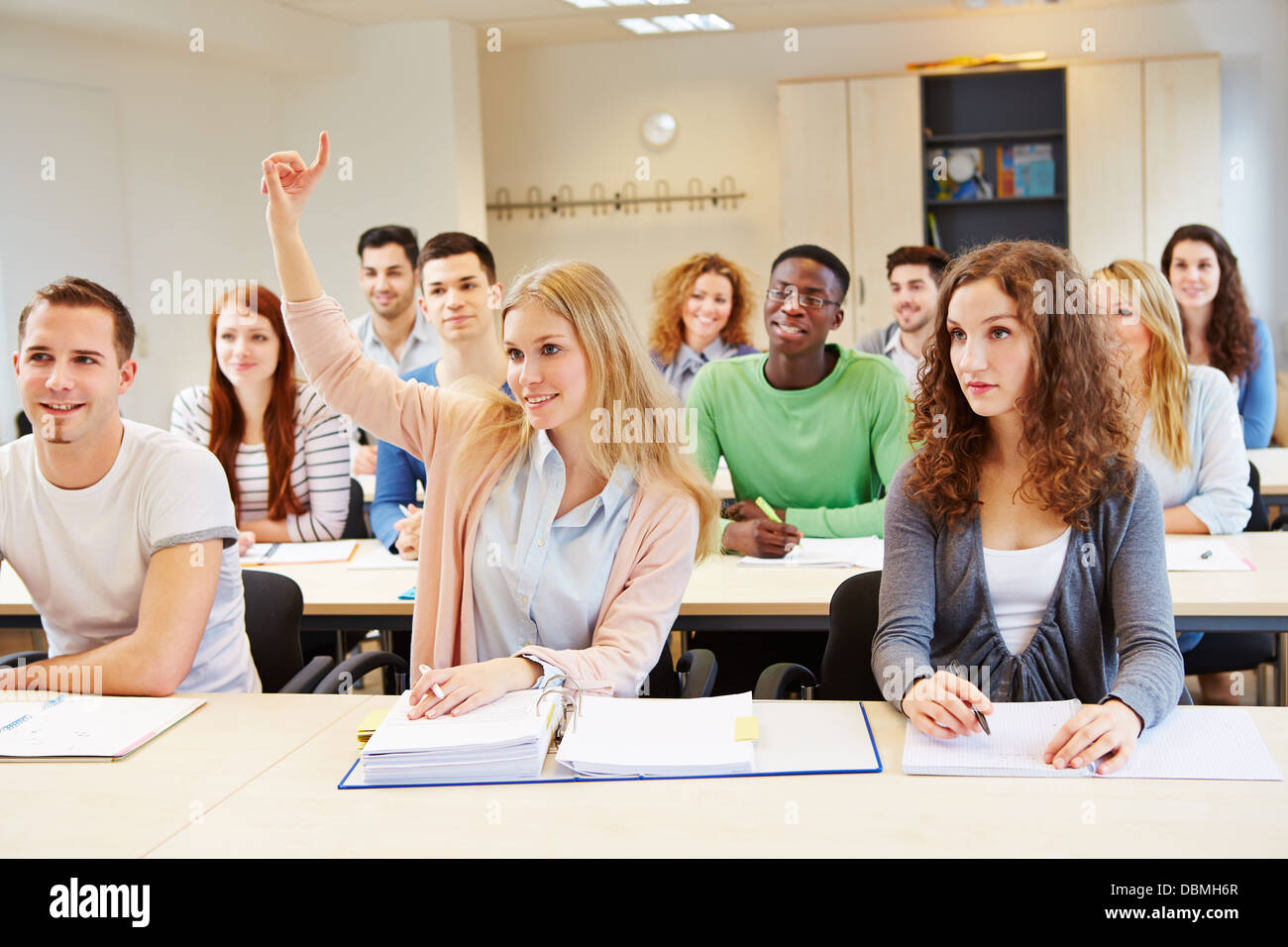 Diligent female student lifting hand in university seminar classroom ...
