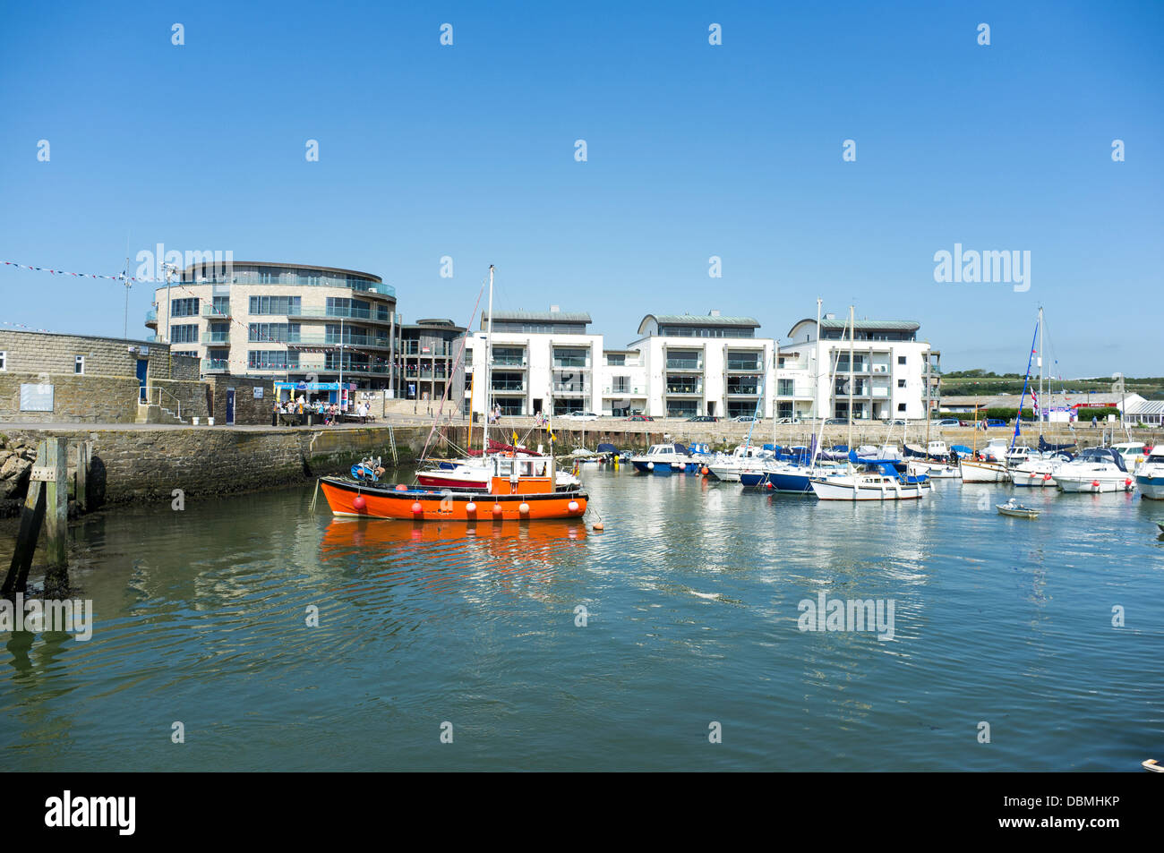 Small orange fishing boat and pleasure craft in West Bay Harbour Dorset ...
