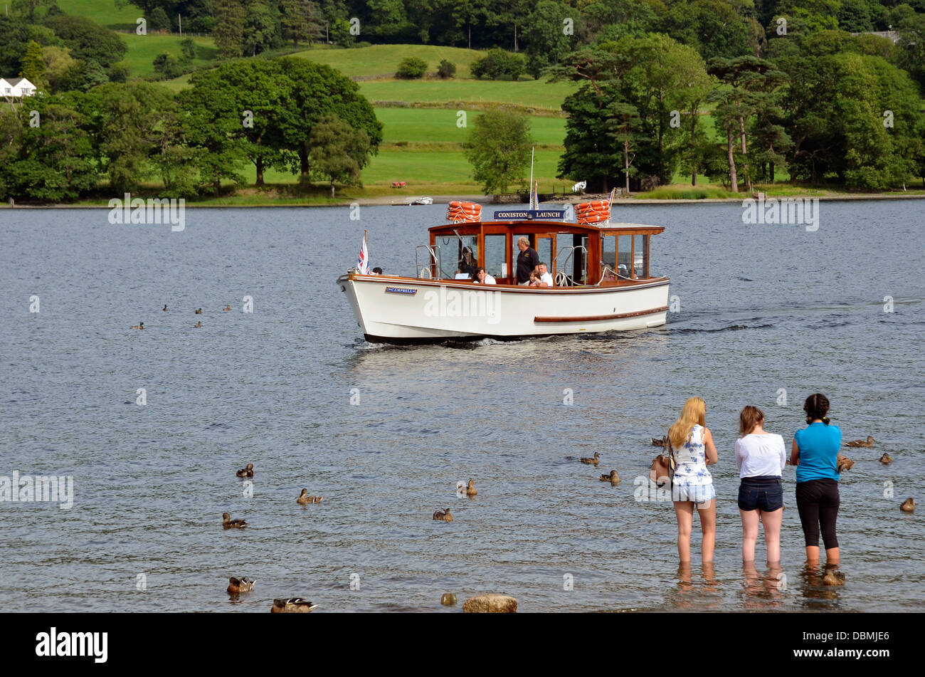 Coniston Launch, approaching Coniston Pier with young women paddling on ...