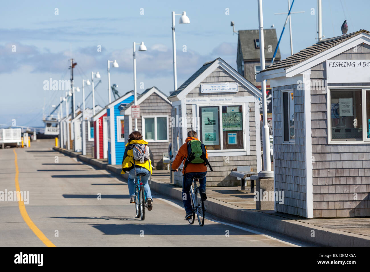 Two people riding bicycles on a boat dock by the ocean bay Stock Photo ...
