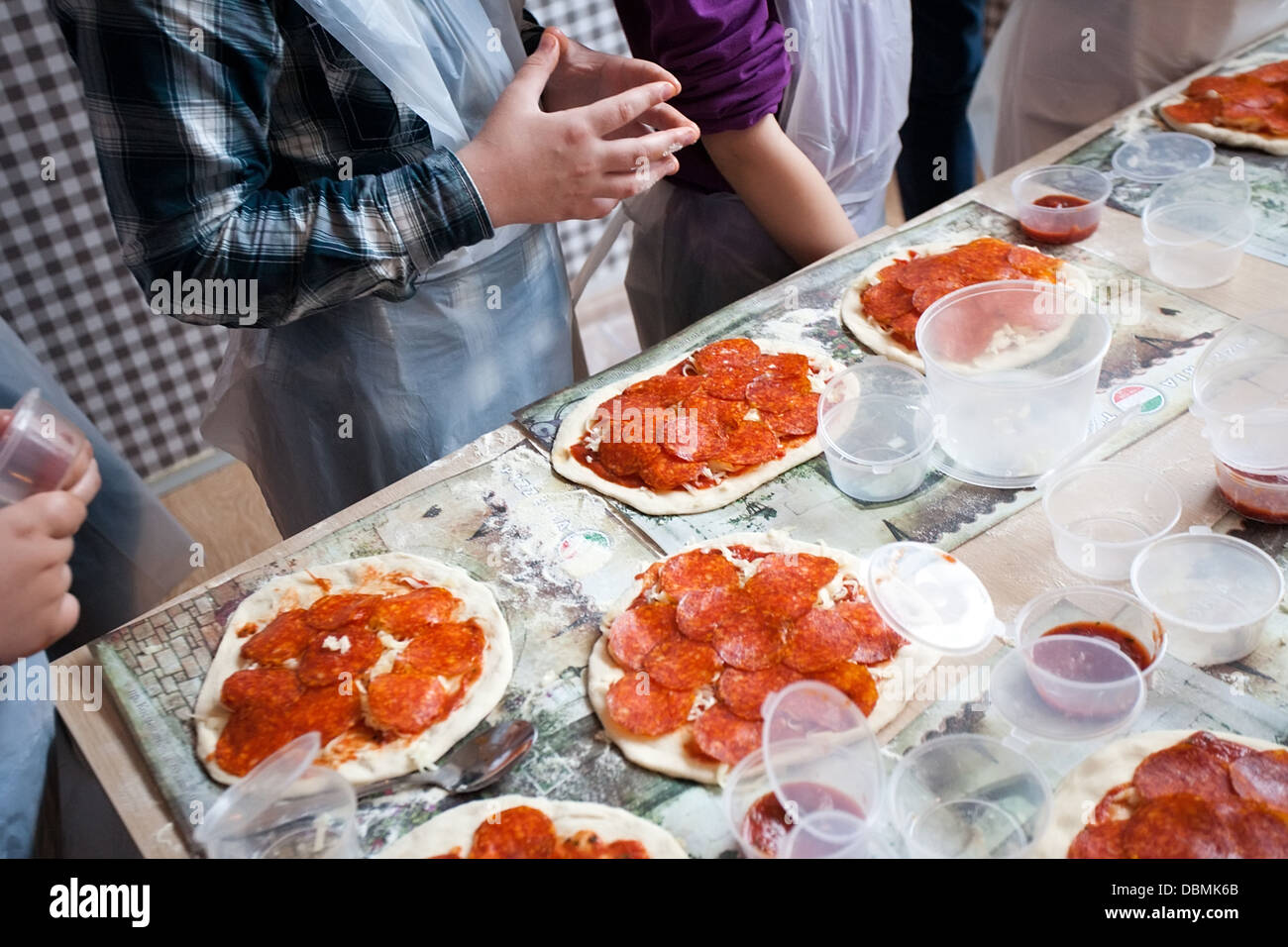 closeup of cook's arms and several pizzas on the table Stock Photo - Alamy