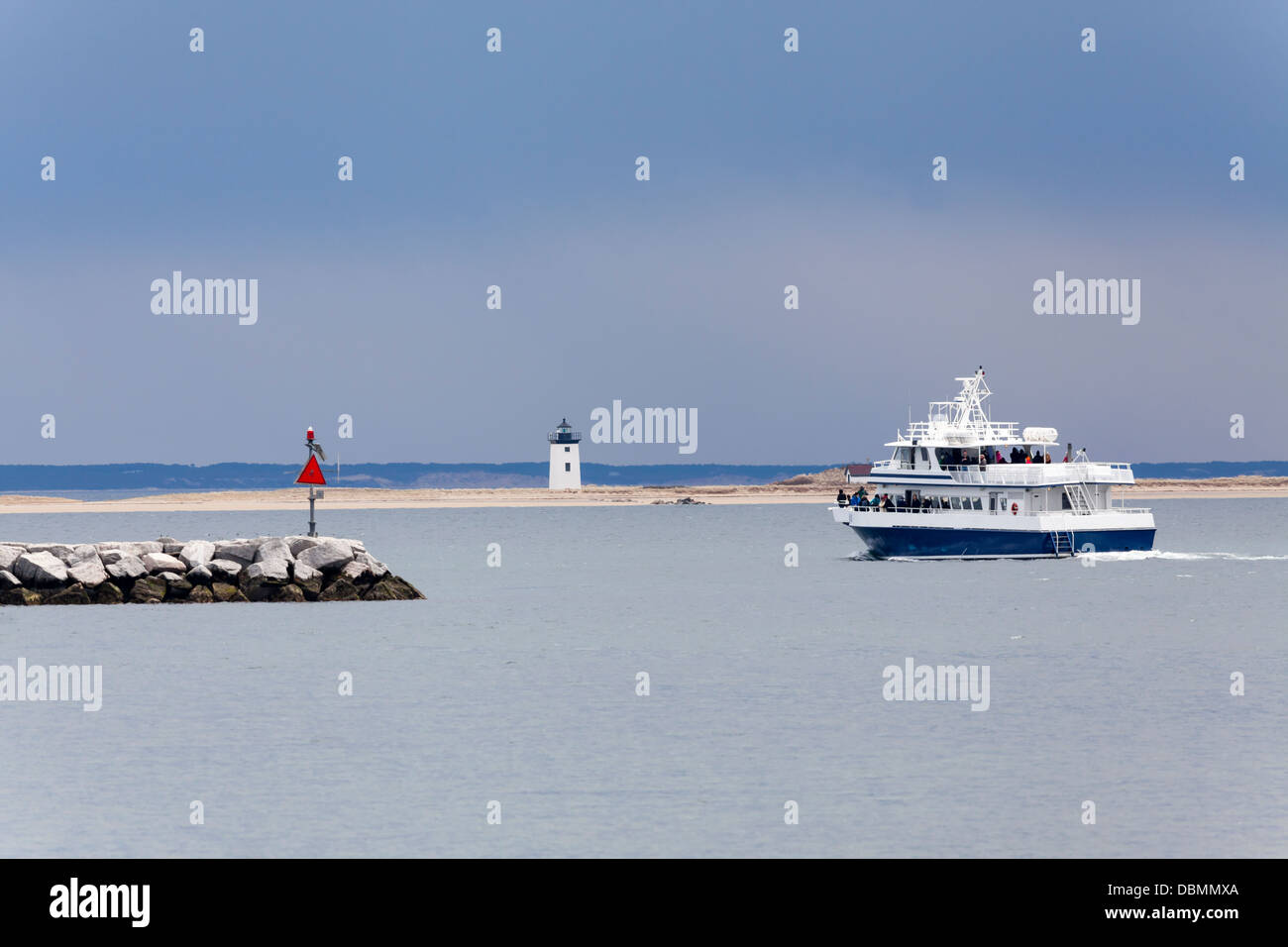 A lighthouse on the ocean bay and a tourist boat with tourists and ...