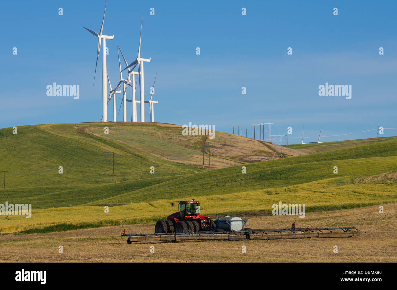 Wind turbines look over agricultural fields and equipment. Oregon, USA ...