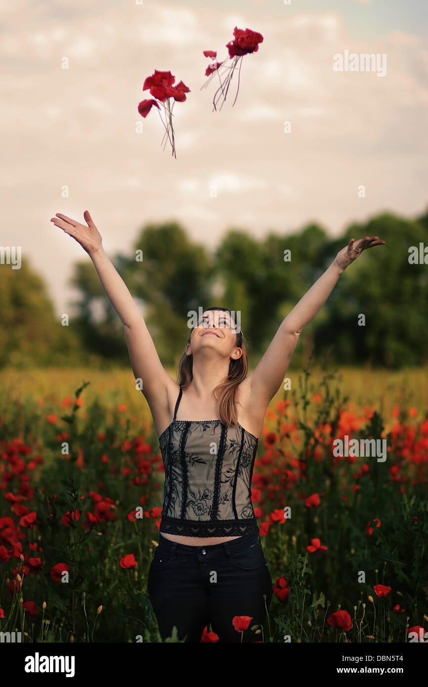 Young woman playing with poppies in a poppy field, Croatia, Europe ...