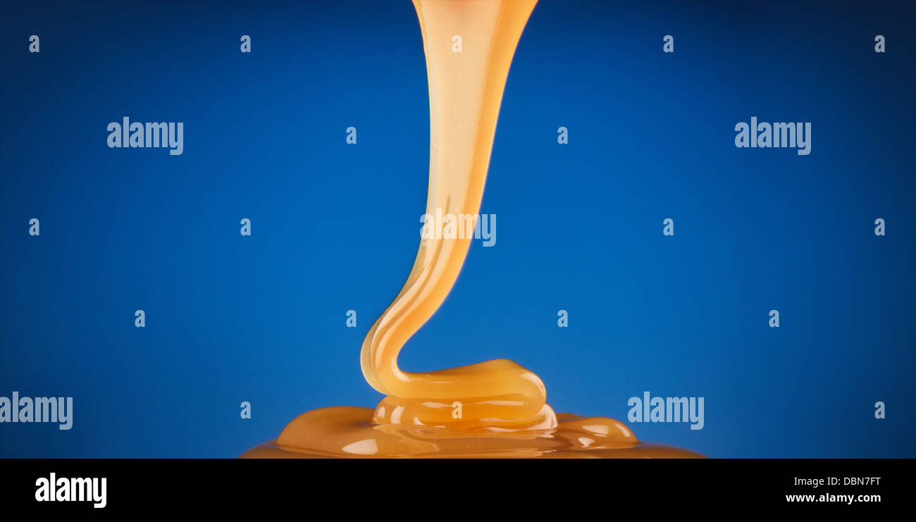 honey, syrup or caramel runs down on a blue background Stock Photo - Alamy