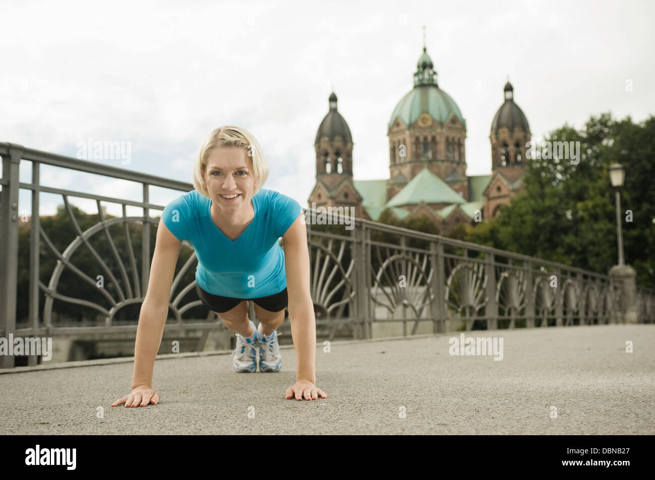 Young woman doing push-ups on bridge, Munich, Bavaria, Germany Stock ...