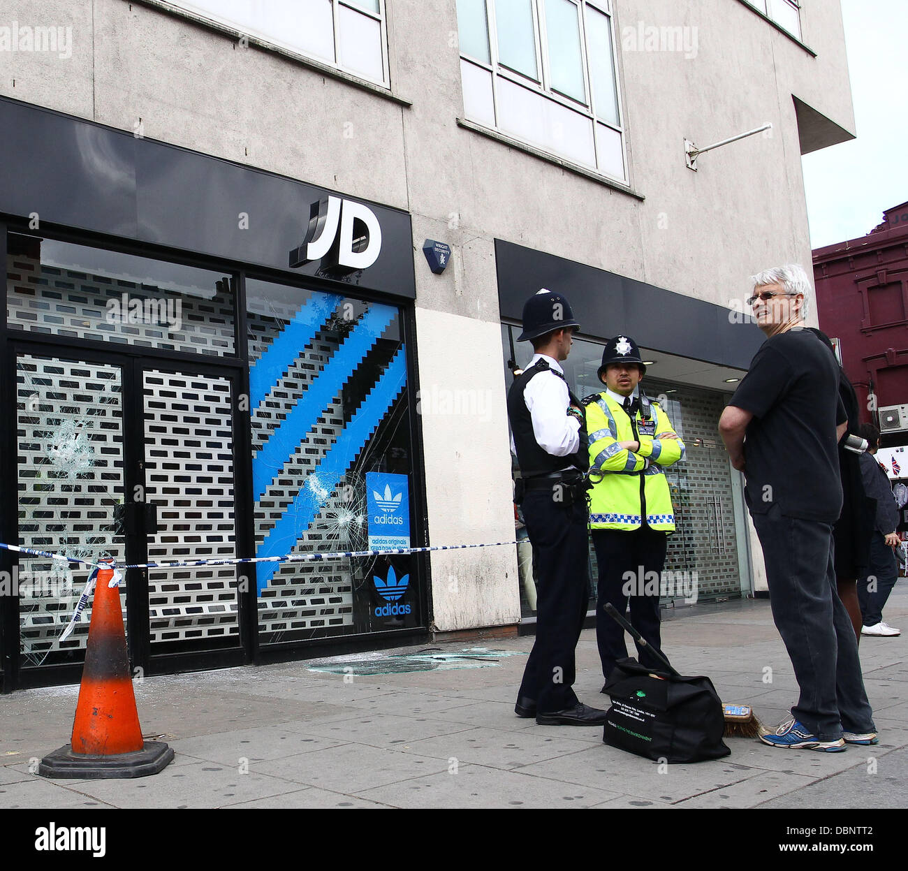 Police stand in front of a JD sports store damaged after a night of ...