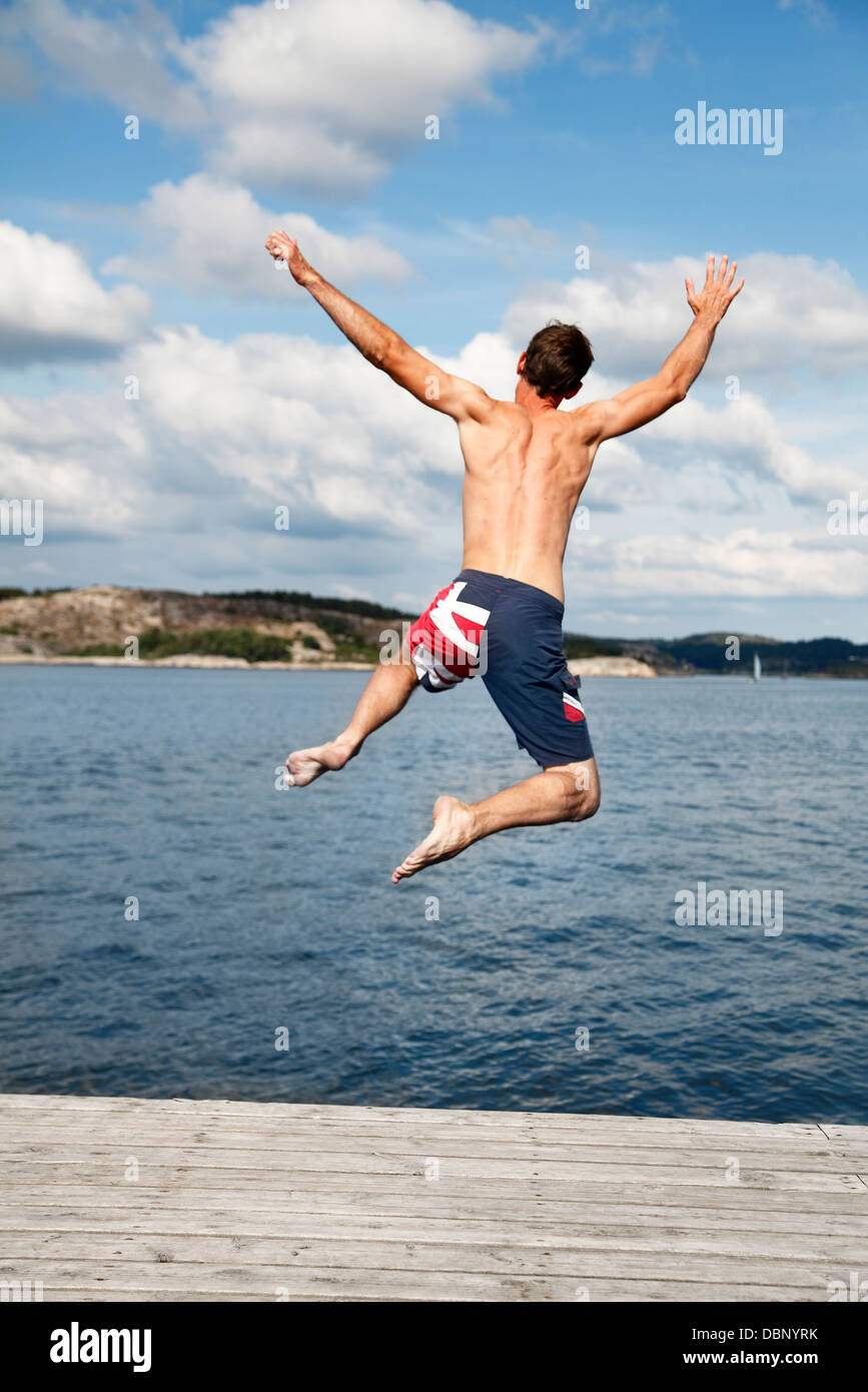 Rear view of man jumping into water Stock Photo - Alamy