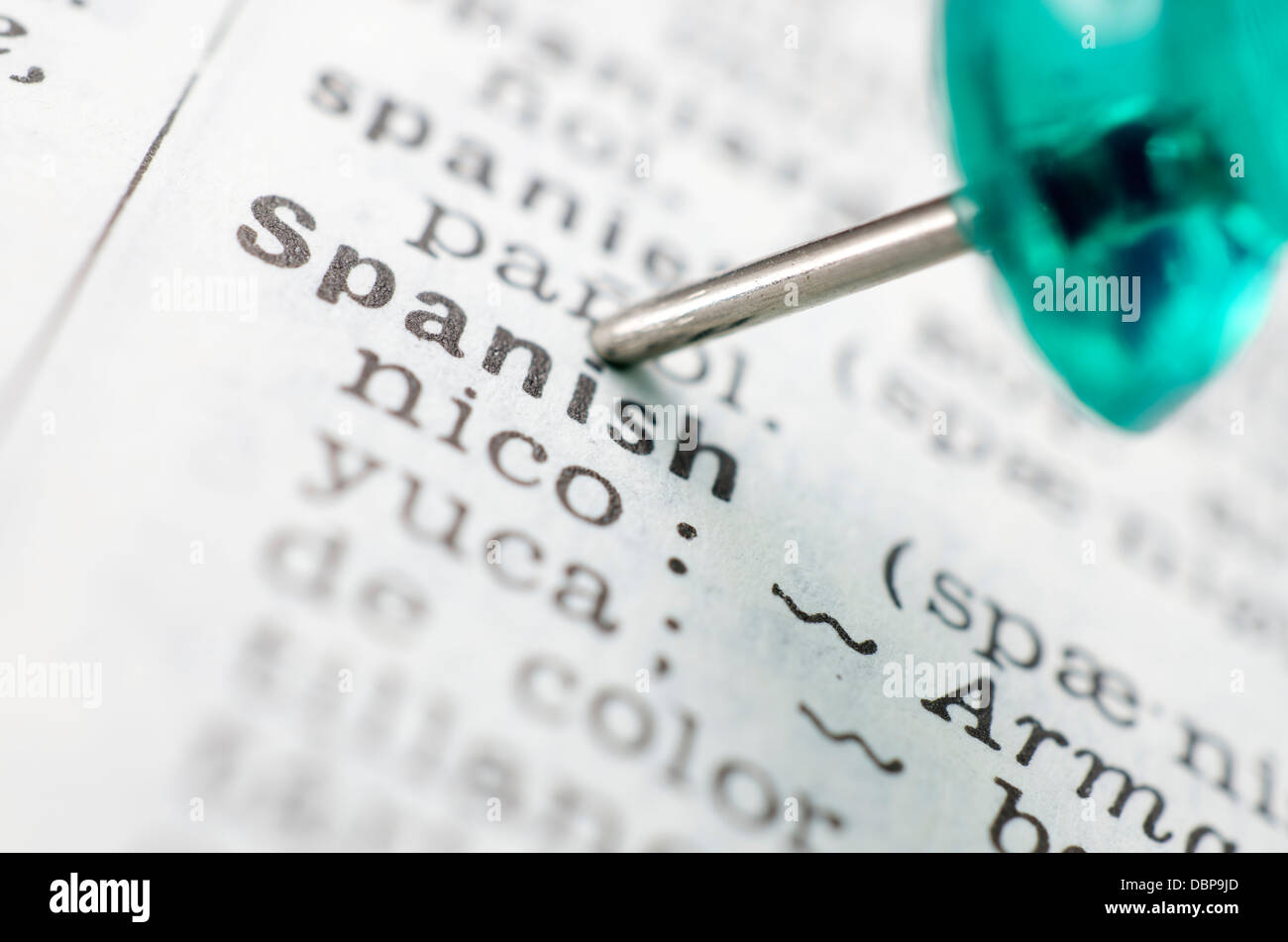 a green pin stuck in the Spanish word Stock Photo - Alamy