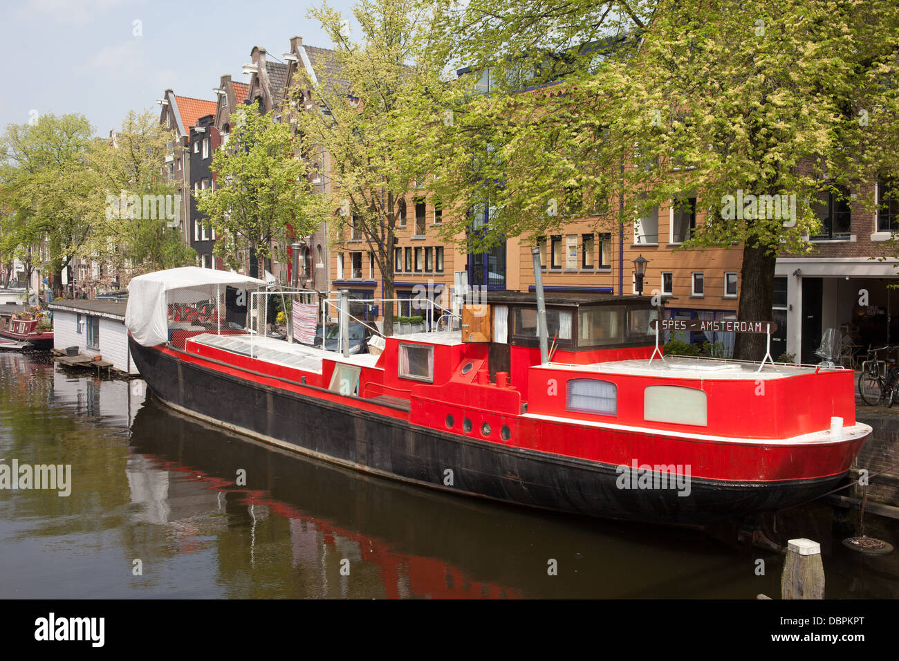 Red painted barge houseboat on a canal in Amsterdam, Netherlands Stock ...