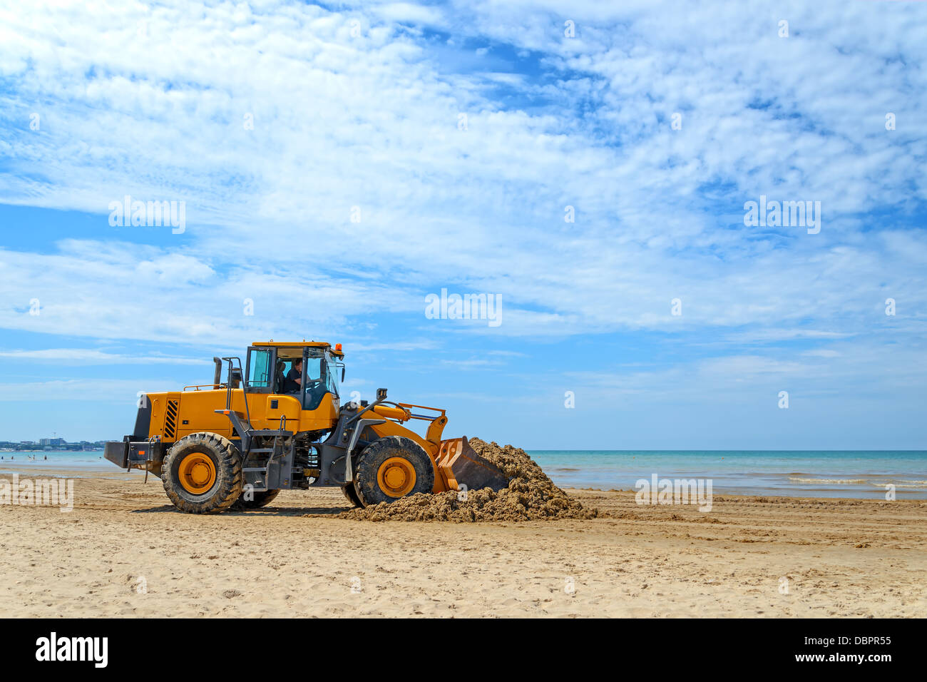 The bulldozer cleans dirt on a beach after a storm Stock Photo - Alamy