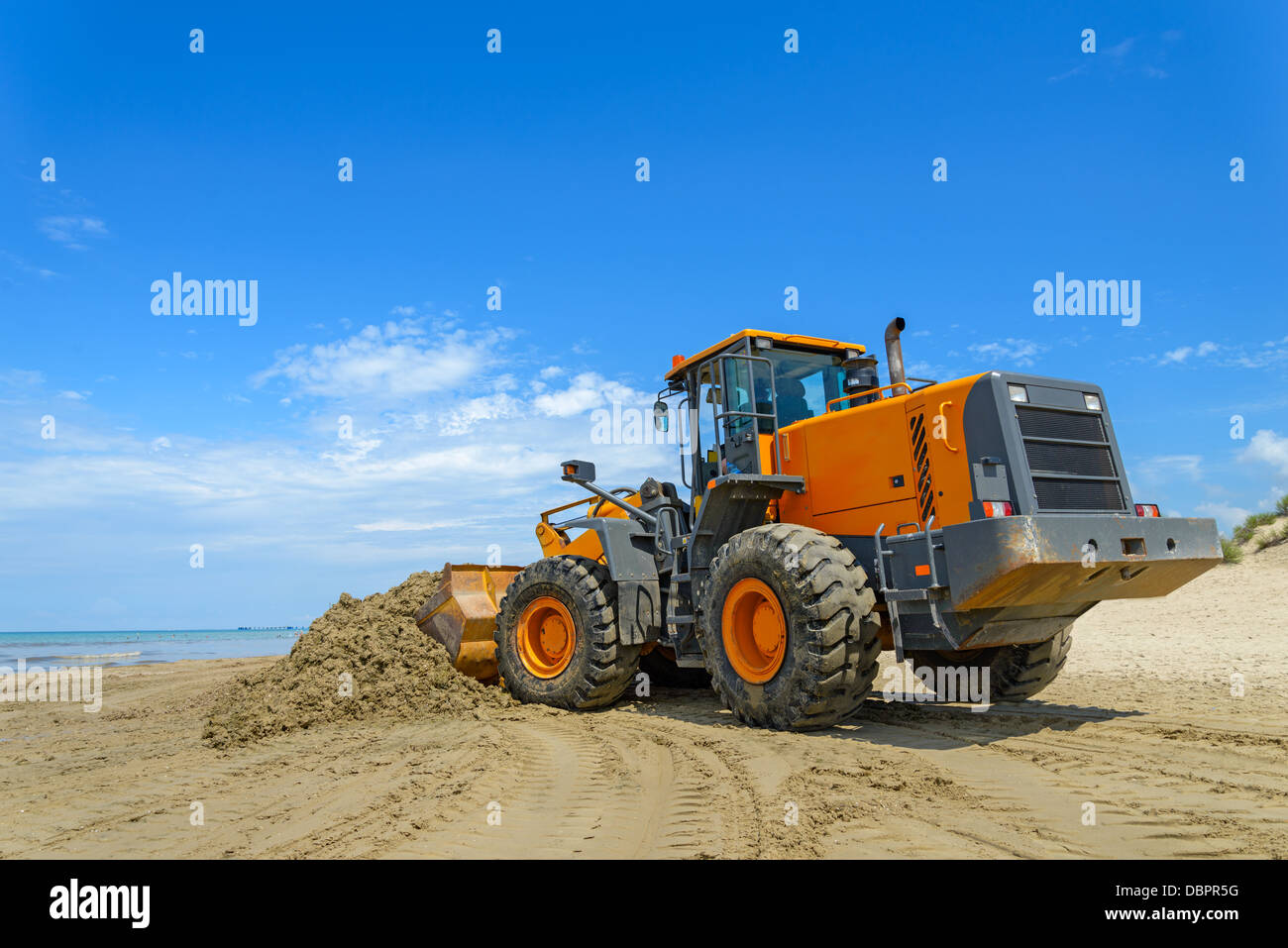 The bulldozer cleans dirt on a beach after a storm Stock Photo - Alamy