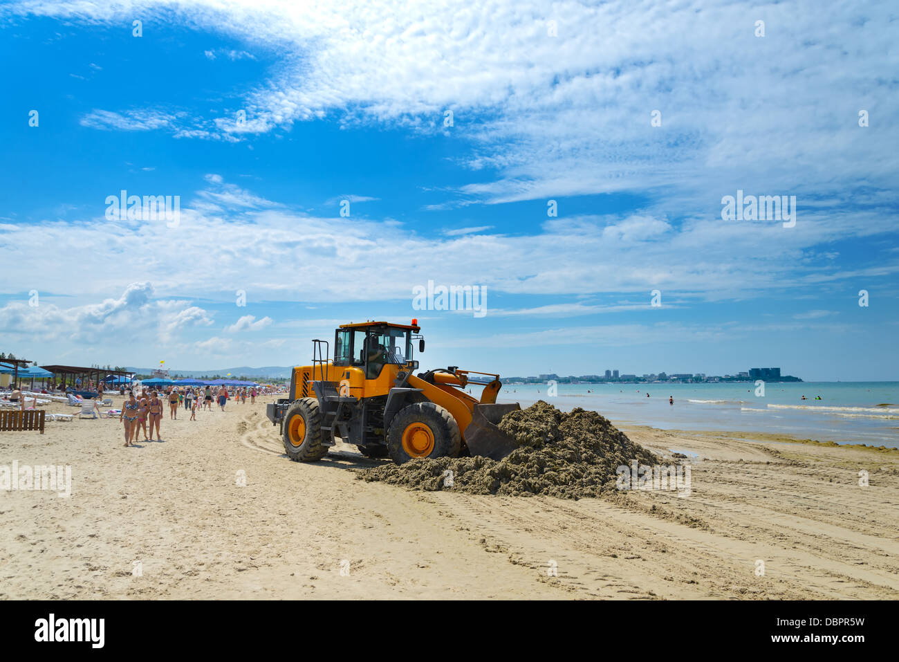 The bulldozer cleans dirt on a beach after a storm Stock Photo - Alamy