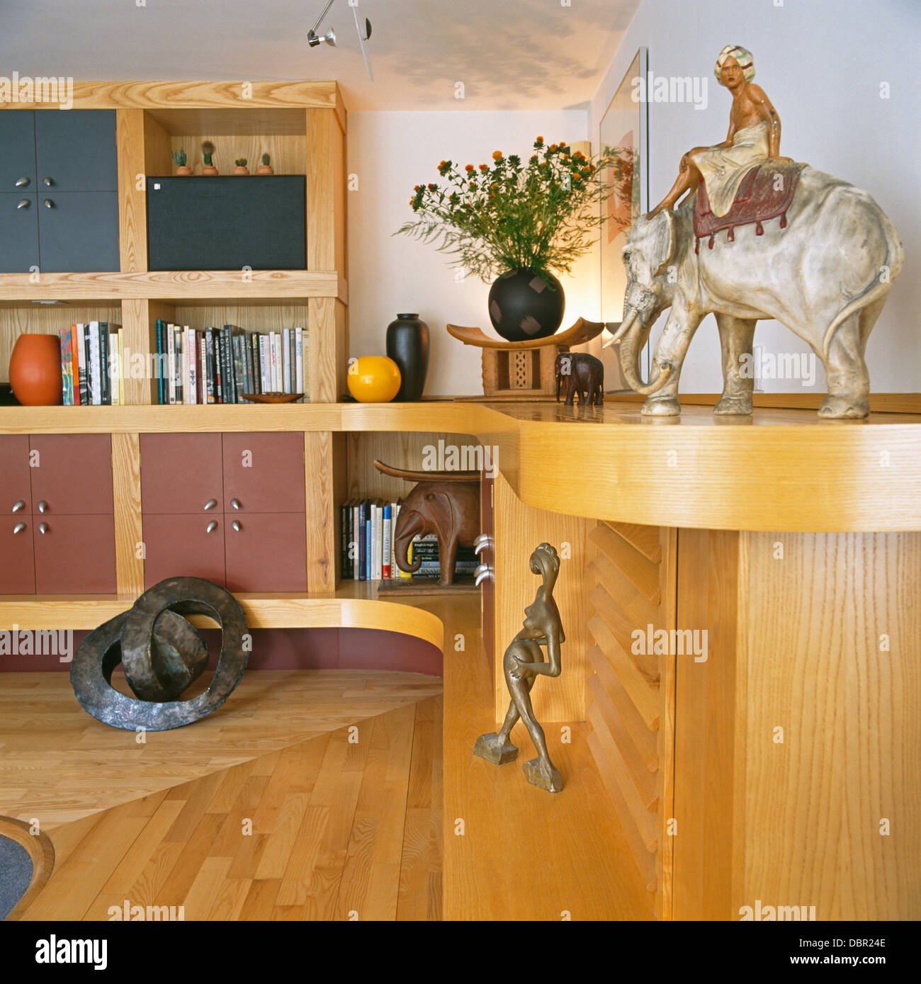 Traditional and modern statues and sculpture on pale wood fitted shelf ...