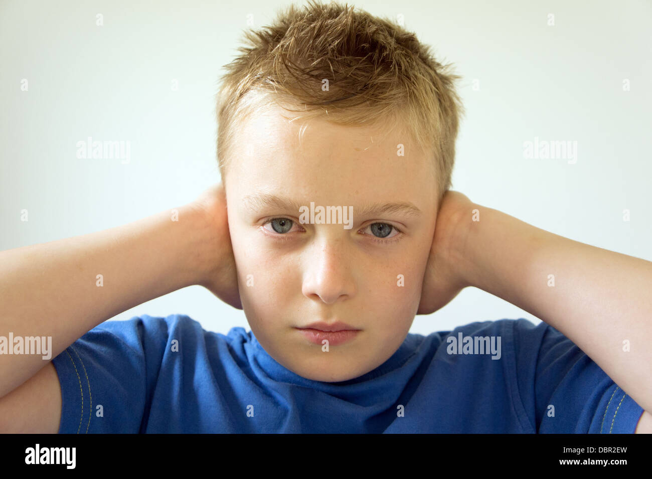 Boy standing with his hands over his ears showing he's not listening ...