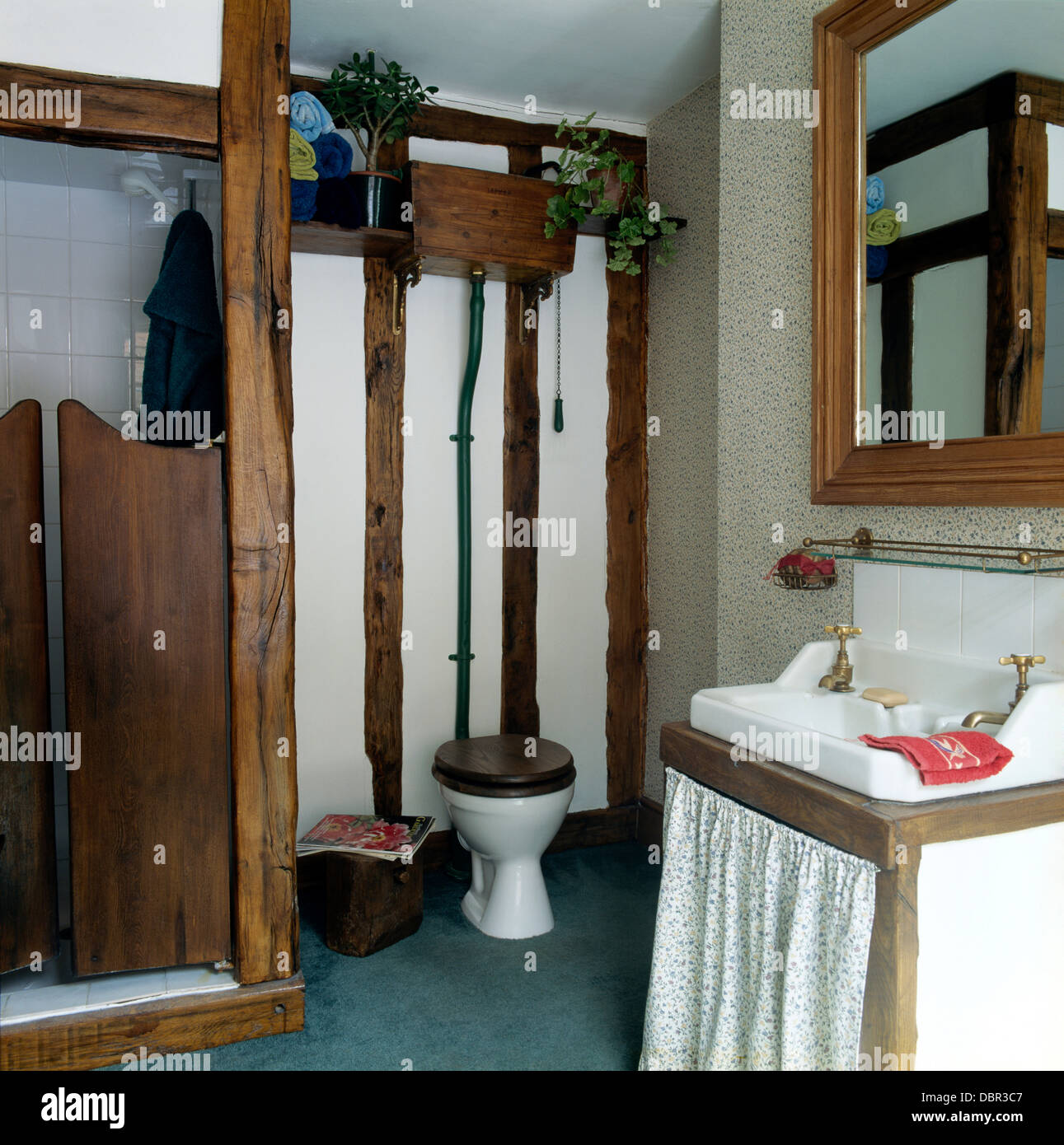 Wooden cistern above toilet in cottage bathroom with wooden swing doors ...
