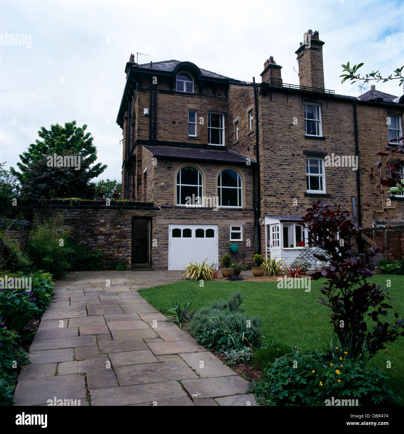 Stone paved path beside lawn in garden of large traditional house in ...