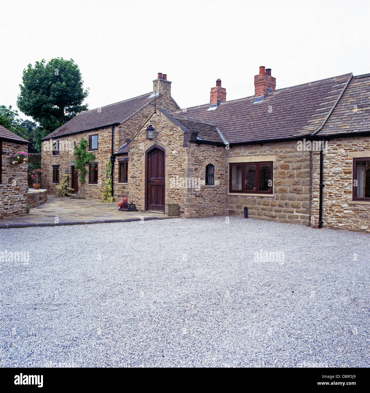 Gravel area in front of well-maintained stone cottage with porch and ...