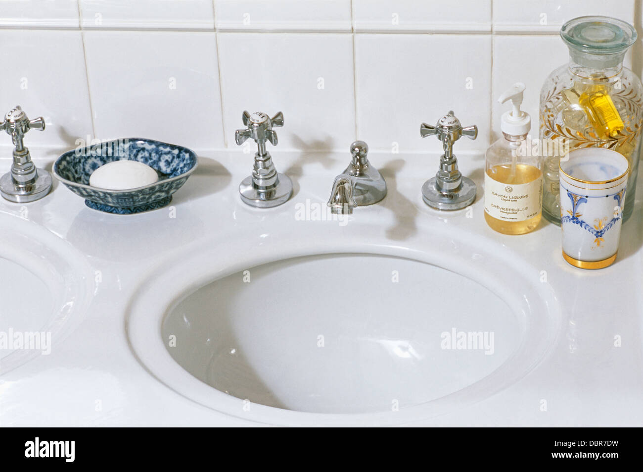 Close-up of bottles of bath oil on white porcelain basin with chrome ...