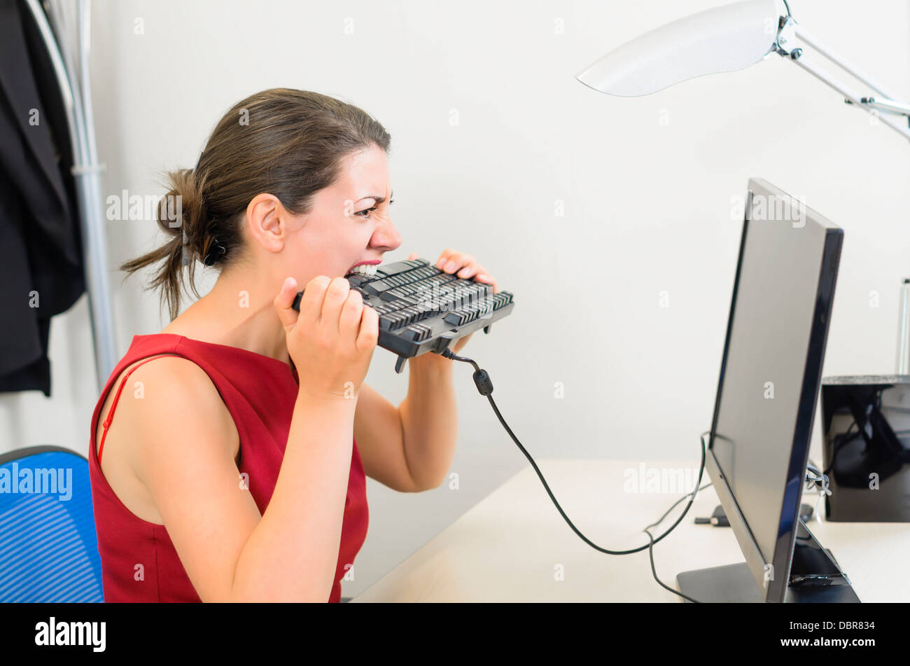Angry businesswoman biting the keyboard Stock Photo - Alamy