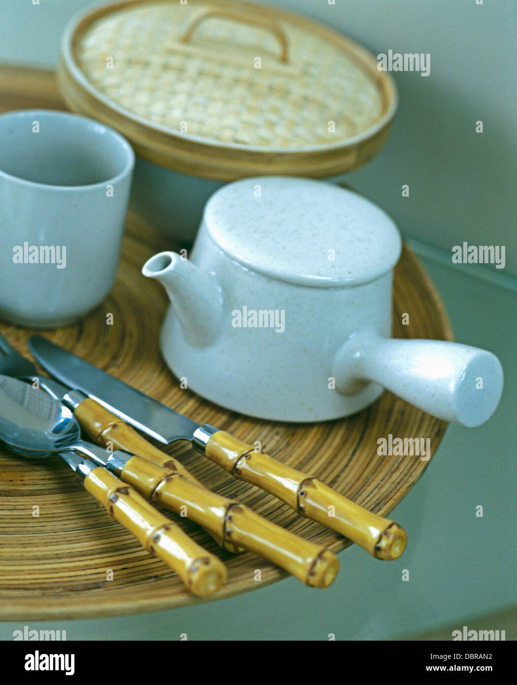 Close-up of pale blue pottery teapot and cup on circular bamboo tray ...