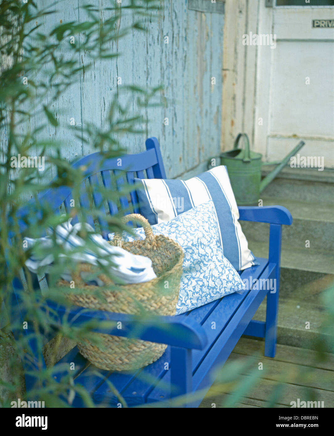 BLue+white striped and floral cushions on bright blue bench on cottage ...