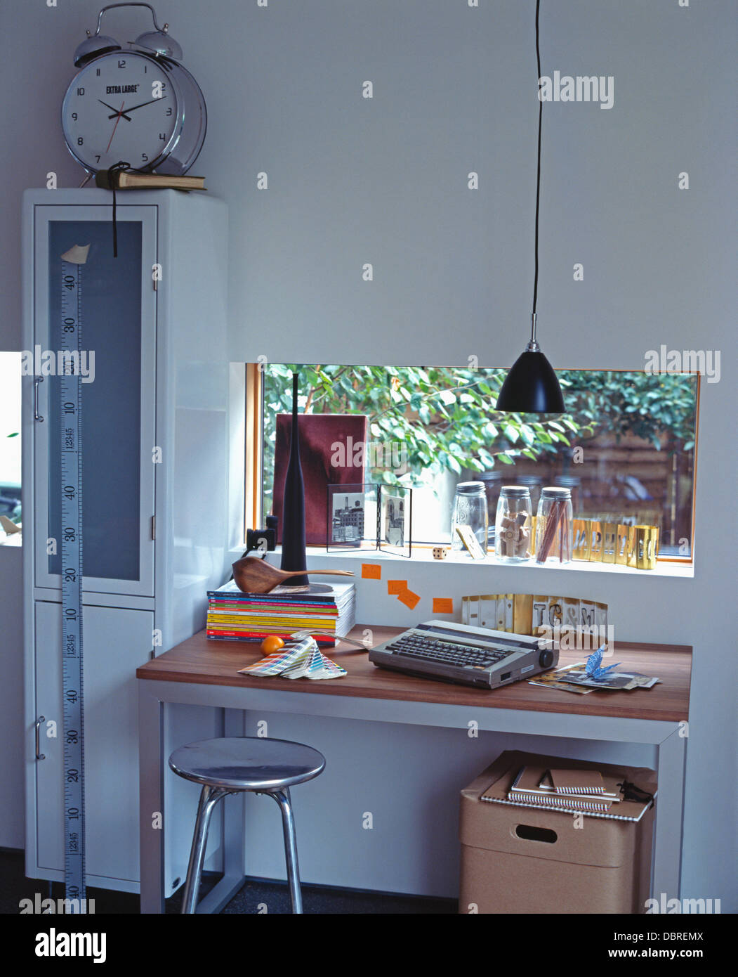 Large stainless-steel alarm clock on tall cupboard beside simple table ...