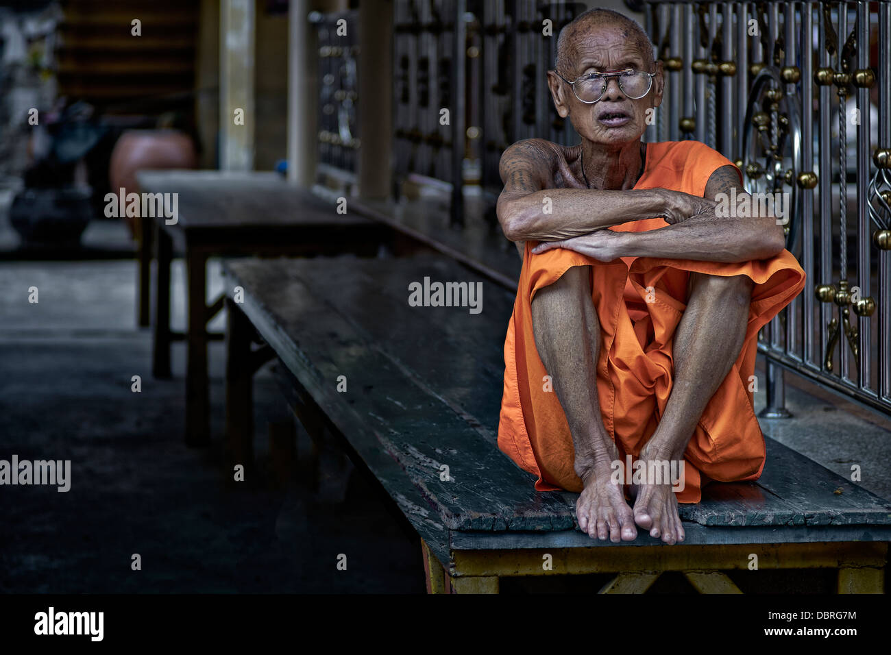 Elderly monk squatting on a bench. Thailand S. E. Asia. 80 year old ...