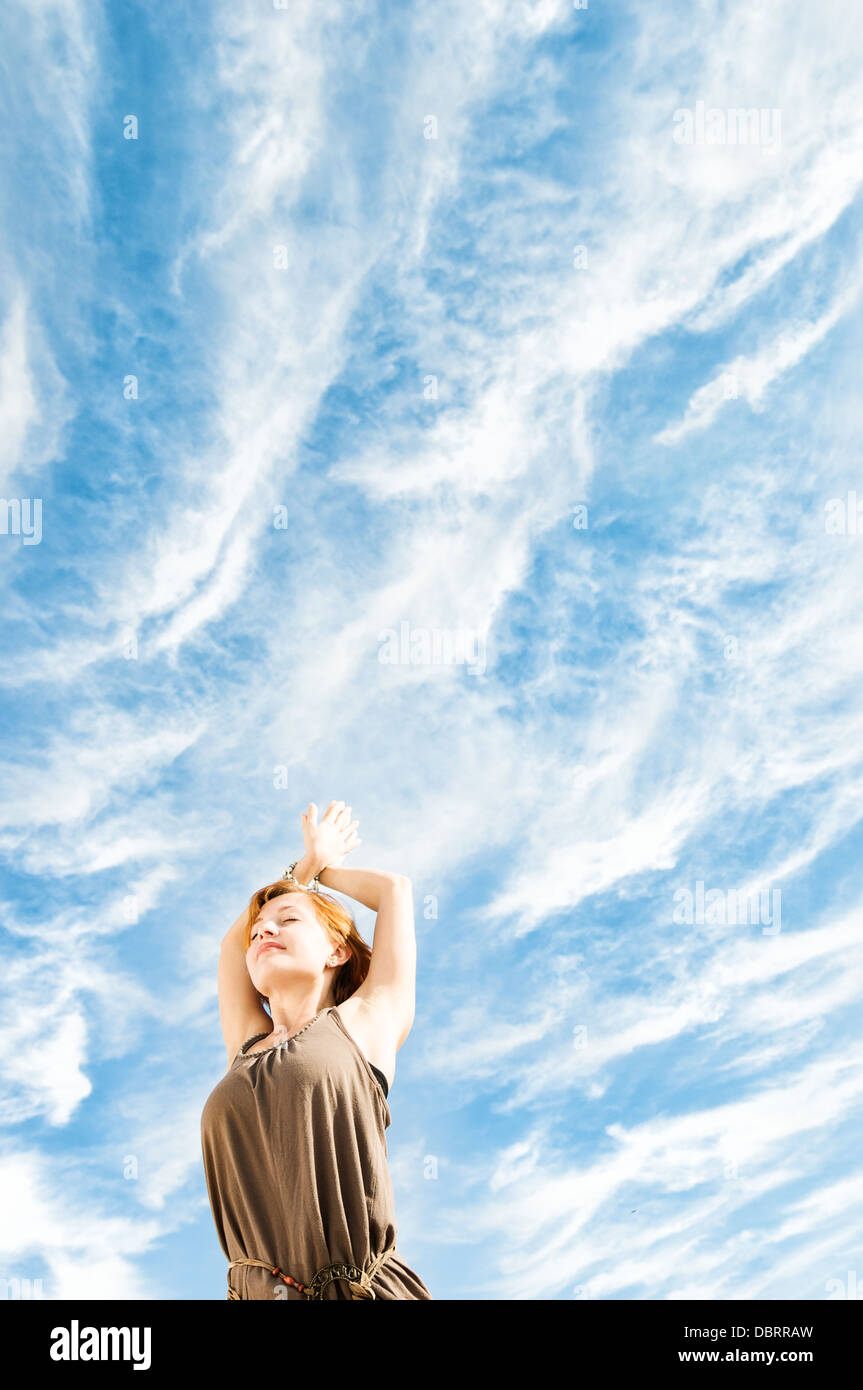Beautiful young dancer performing yoga-dance outdoors with blue sky and ...