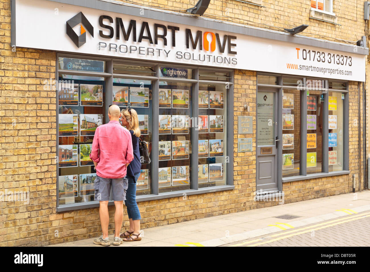 Couple looking at properties for sale or rent at an estate agent shop ...