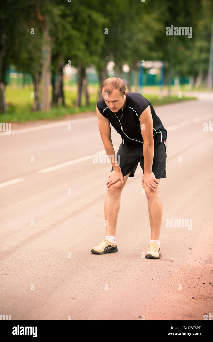 Sportive young man runner having rest after jogging on a road Stock ...