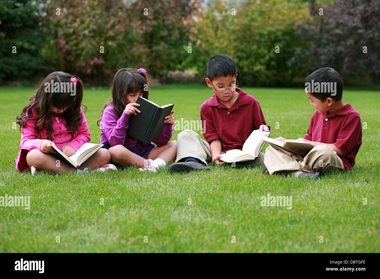 multi ethnic group of kids reading in grass Stock Photo - Alamy
