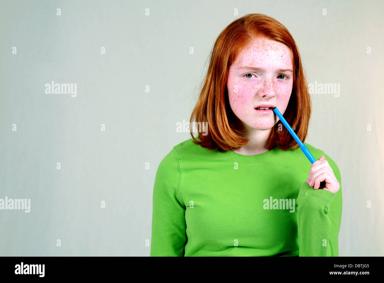 pretty red haired girl chewing on a pen Stock Photo - Alamy