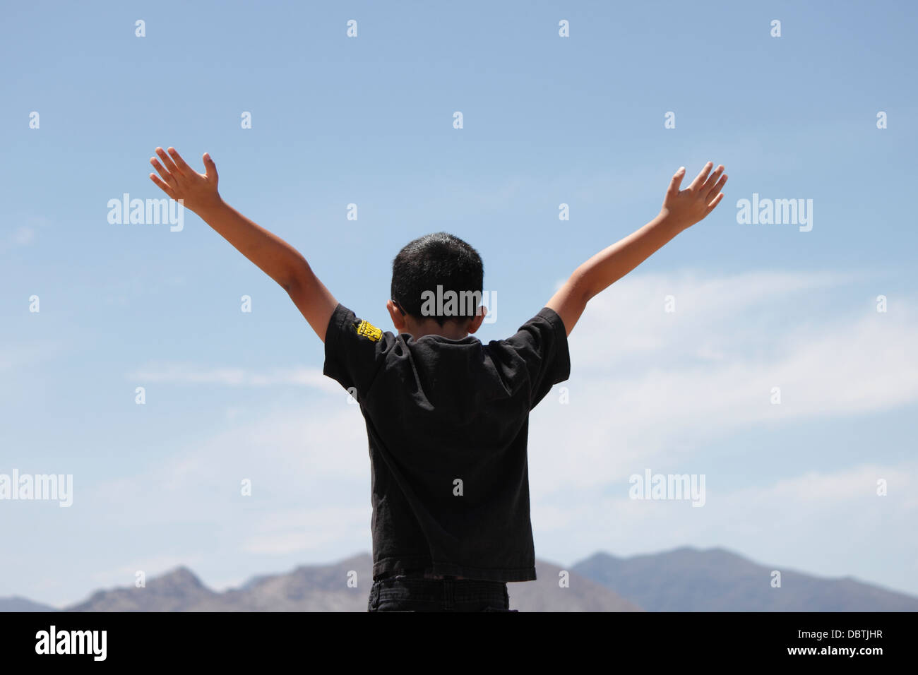 A young boy with his arms spread out wide against the blue sky Stock ...