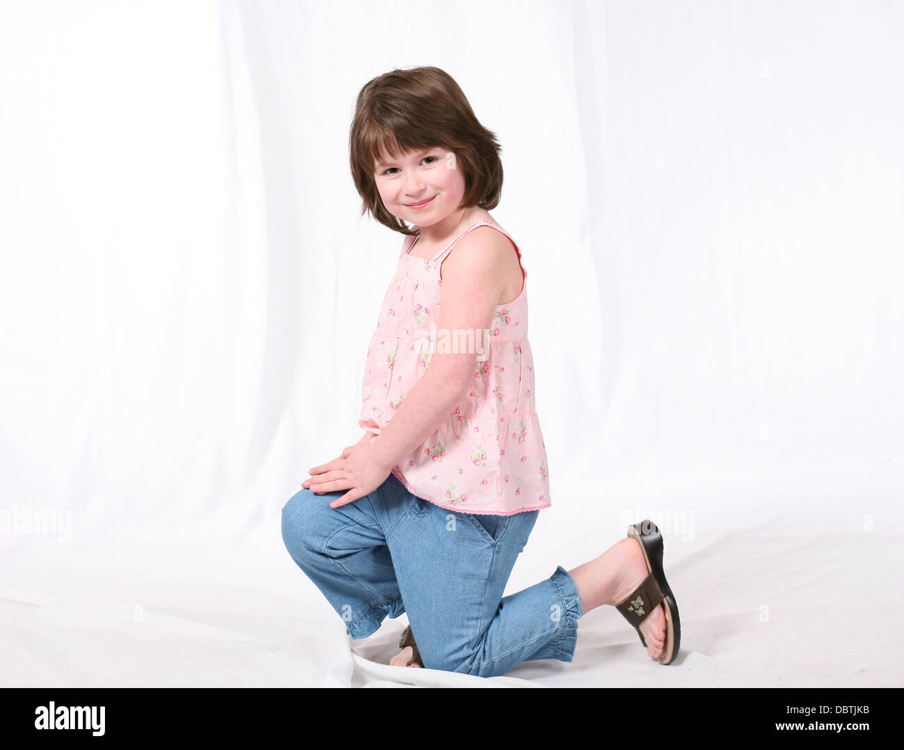 pretty brunnete little girl kneeling on white background Stock Photo ...