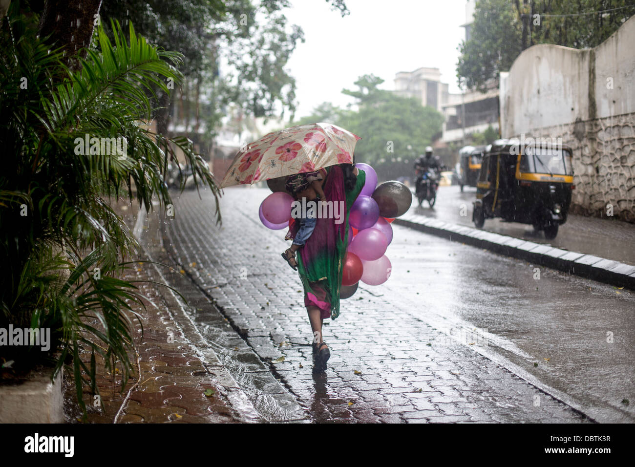 Woman walking with child and balloons in rain Stock Photo - Alamy