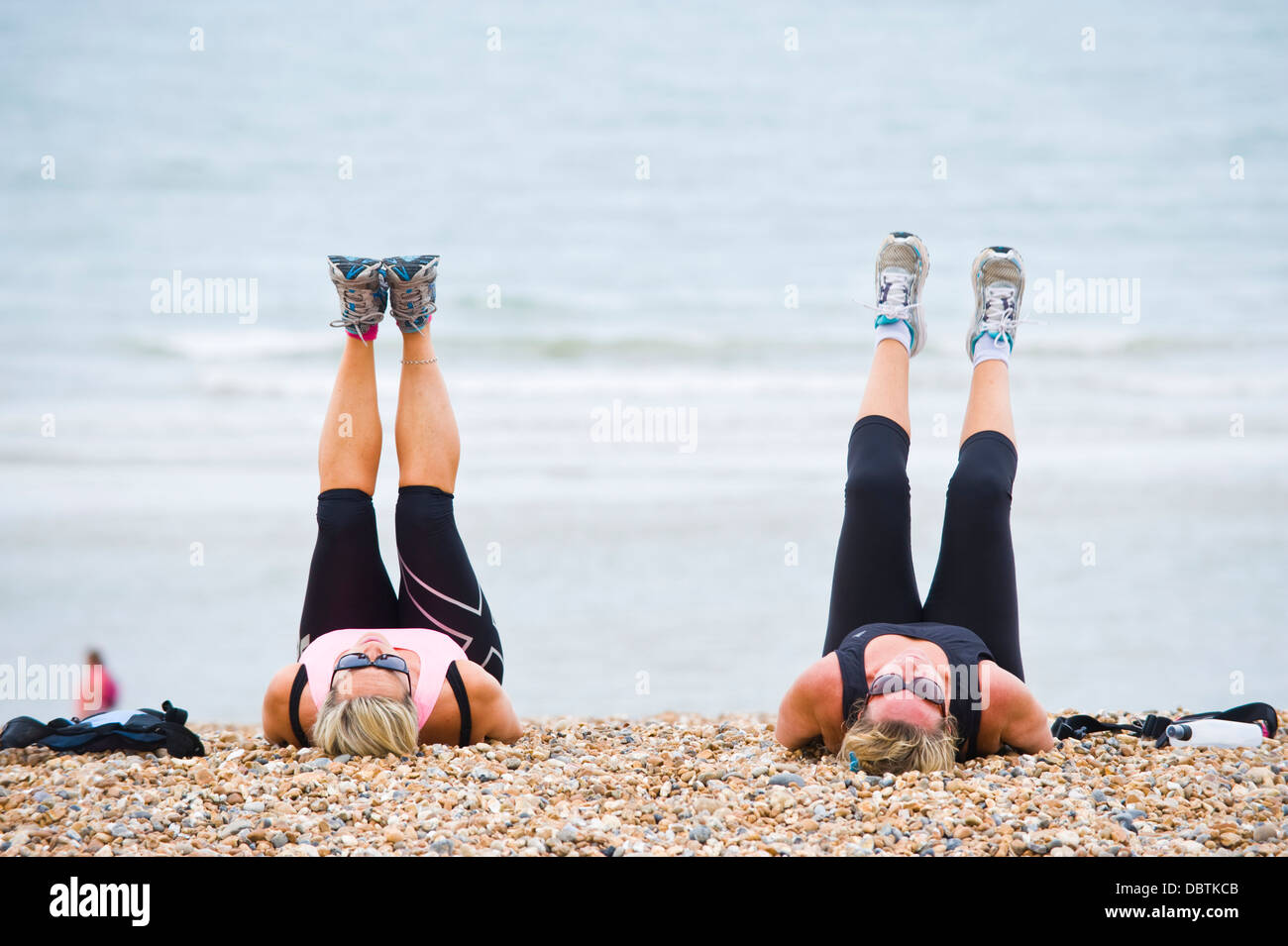 Two mature women having an early morning fitness workout on the beach ...
