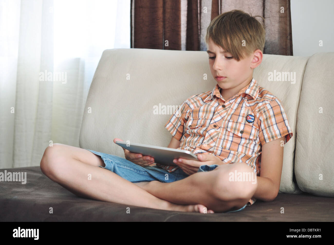 Boy using a tablet computer in a living room Stock Photo - Alamy
