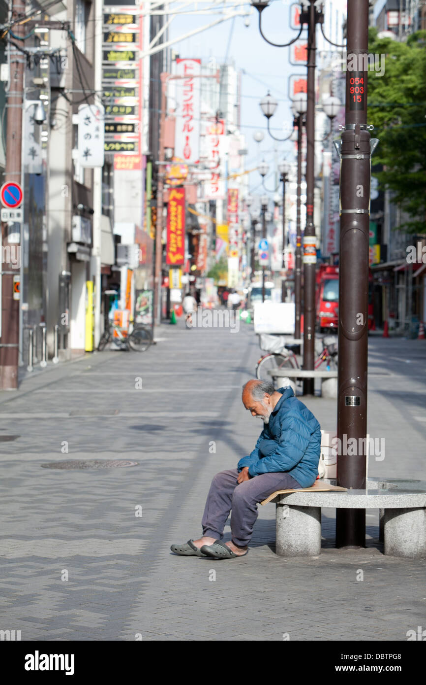 A homeless man sits on a Saturday morning in Nanba district, Osaka ...