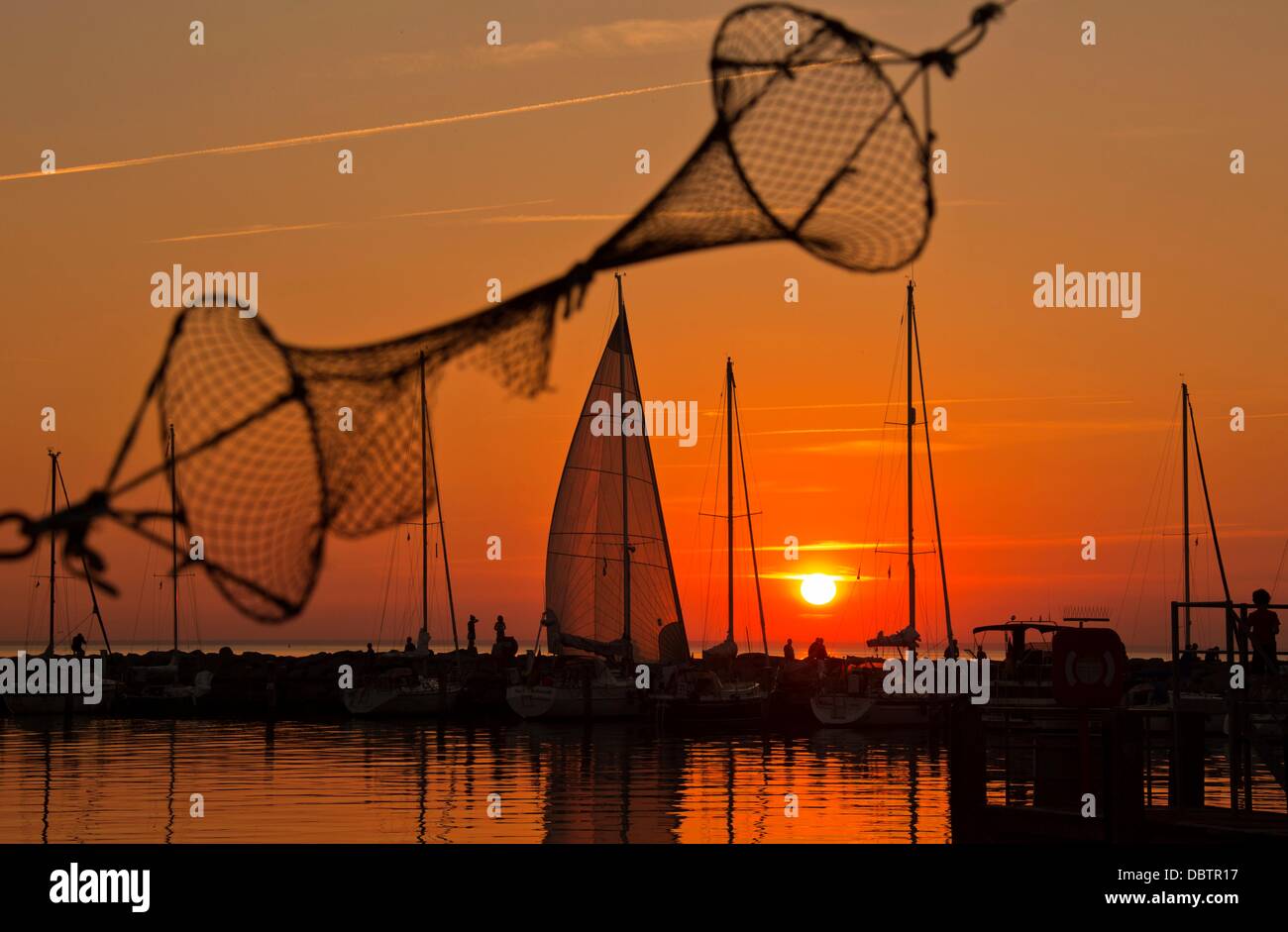 The sky is turned red by the sinking sun at the harbour of Timmendorf ...
