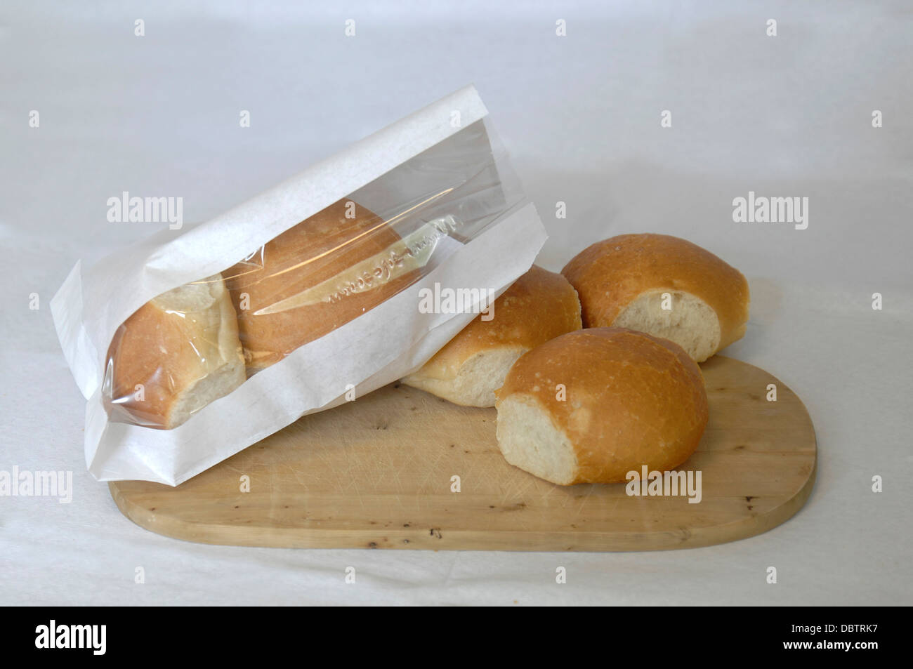 Fresh white crusty rolls on a breadboard Stock Photo - Alamy