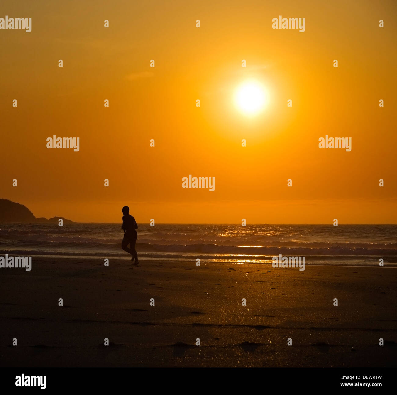 Man running on the beach at sunset Stock Photo - Alamy